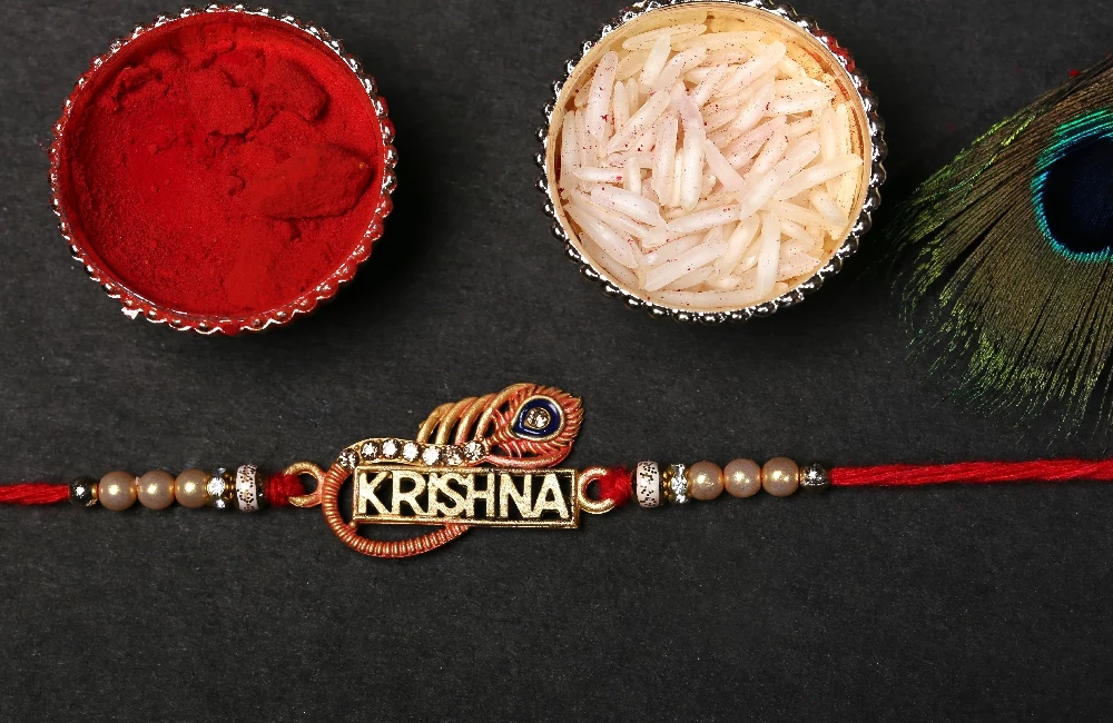 Buy Krishna Rakhi with Metal Feather Online Via The Desi Food